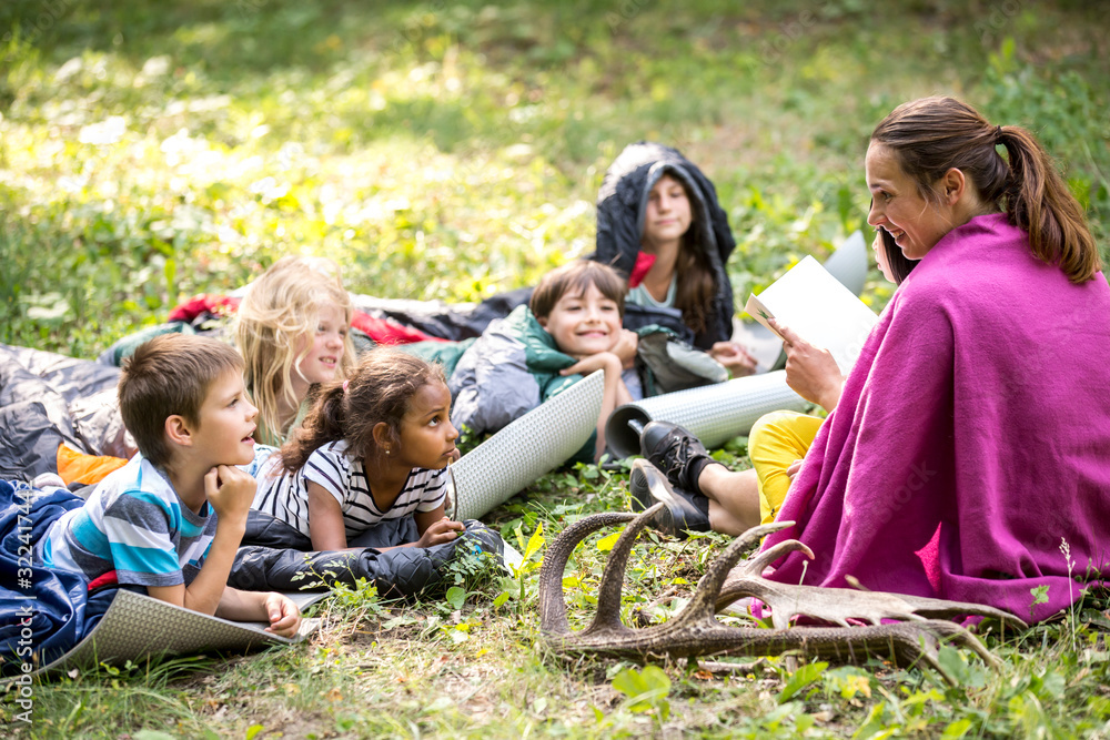 Teacher reading story to school children, camping in the forest Stock ...