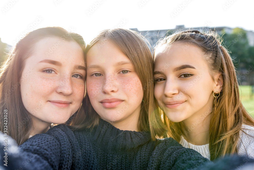 Three teenage girls of 12-14 years old, summer city watching videos ...