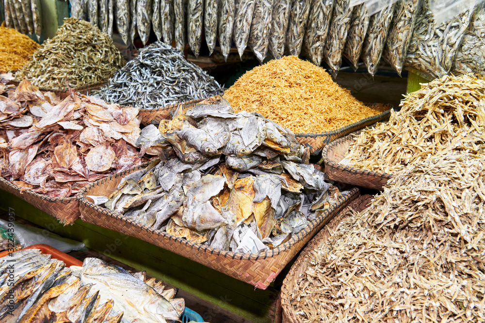 Close-up of heaps of dried and salted small fishes in bamboo baskets at ...