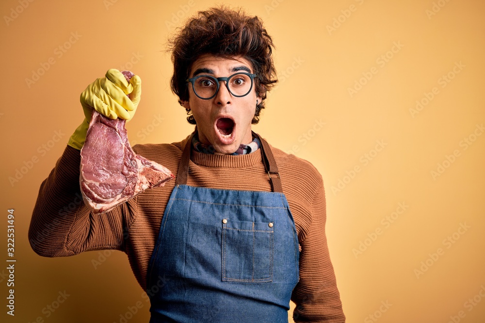 Young handsome butcher man holding meet steak standing over isolated ...
