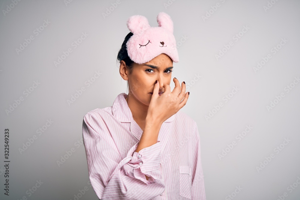 Young beautiful brunette woman wearing pajama and sleep mask over white ...