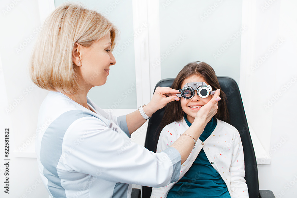 Mixed race girl with optometrist trial frame in vision clinic. Female ...