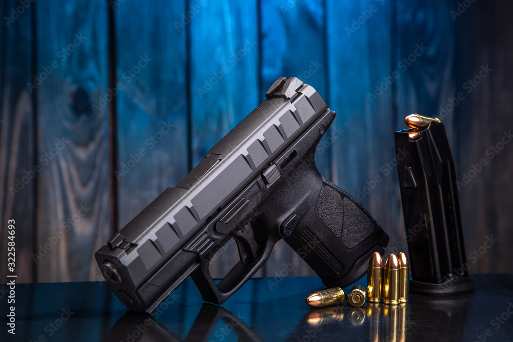 Black modern gun and ammunition for it on dark blue background. Short ...