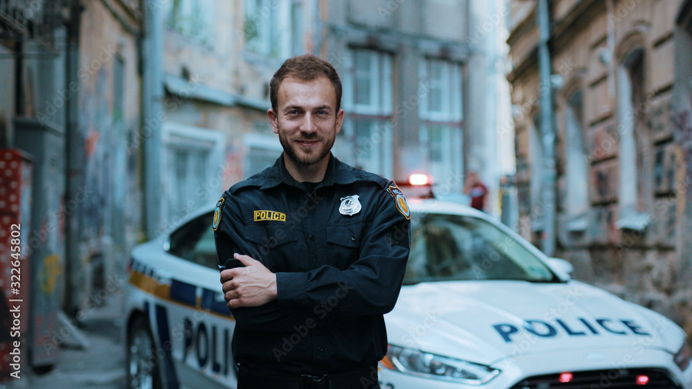 Smiling young man cops stand near patrol car look at camera wear ...
