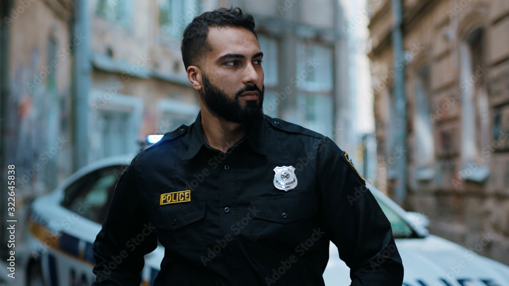 Foto de Handsome young man cops stand near patrol car look at camera ...