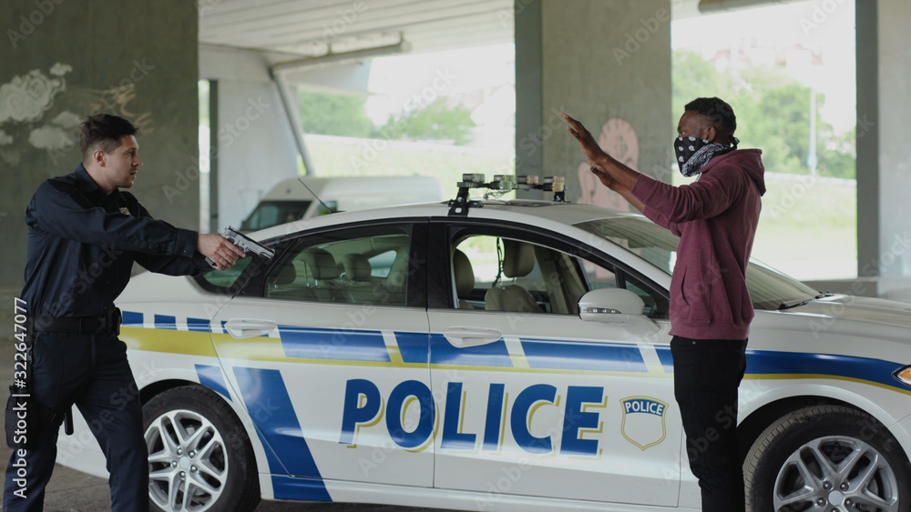 Angry policeman with a pistol standing with a robber in handcuffs ...