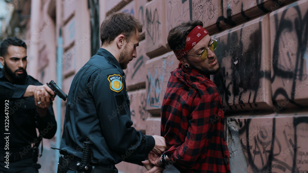 Portrait policeman with pistol arrest robber in handcuffs standing near ...
