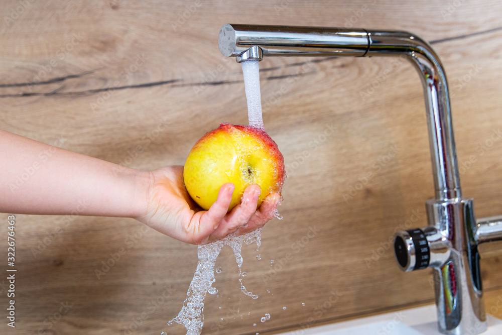 Washing apples in a child's hand. Red apple with water splash on hands ...