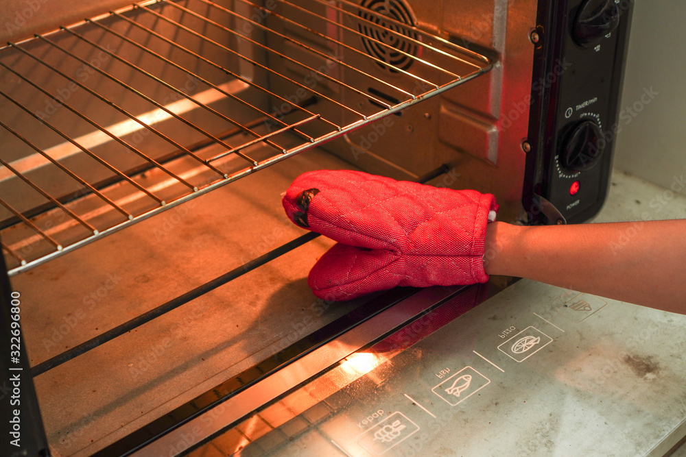 an accident, a hand wearing oven glove touching on hot wire that burns ...