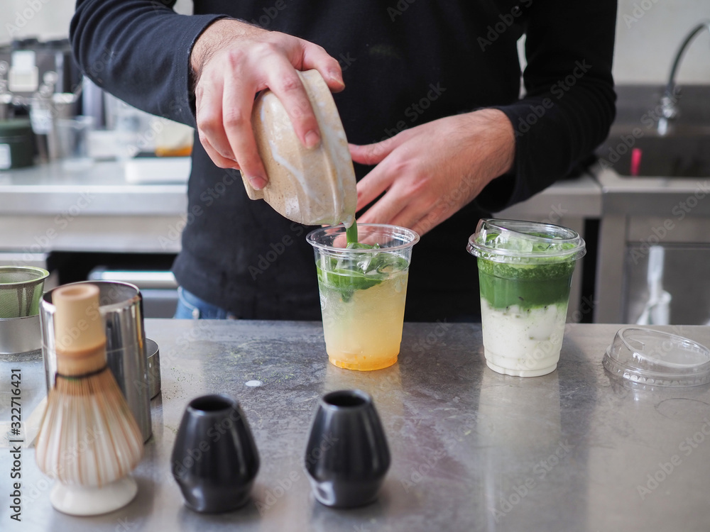 A plastic glass of iced matcha green tea with layer of sparkling water ...