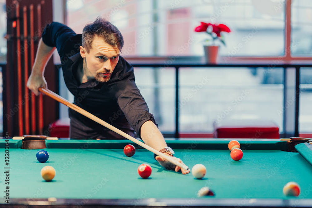 A man tries his hand at playing billiards. He is accompanied by various ...