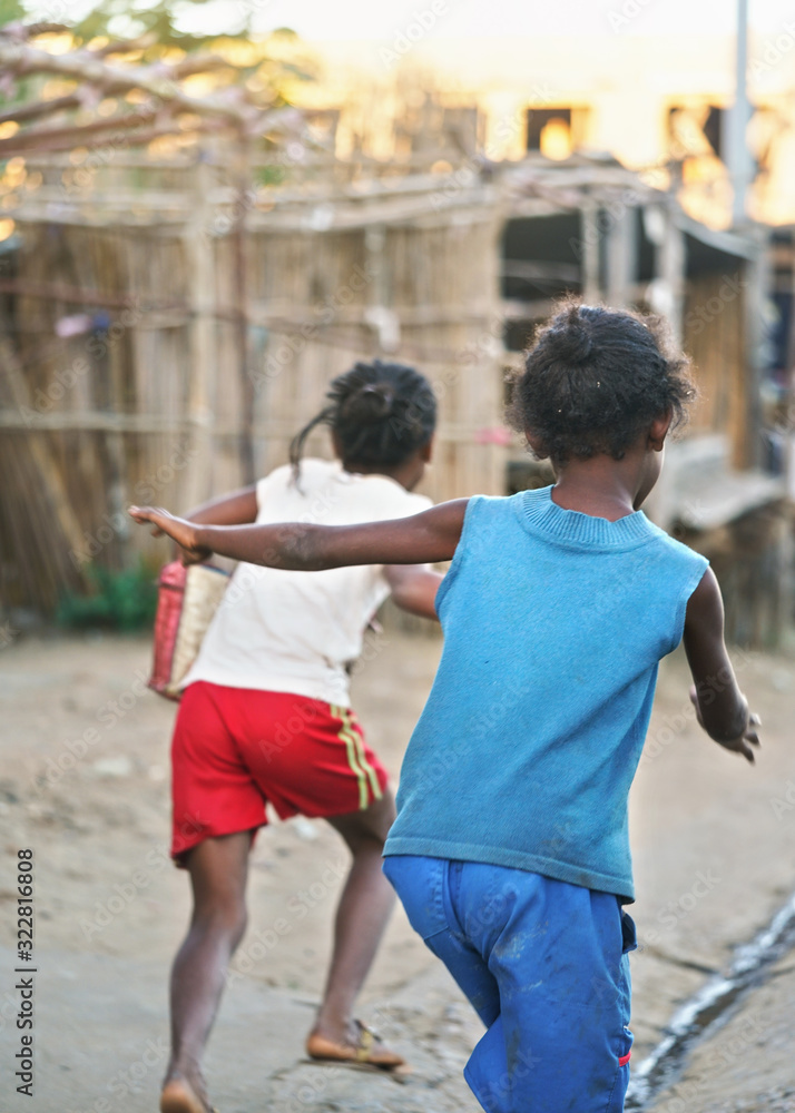 Two African kids playing, running on dusty road, view from behind foto ...