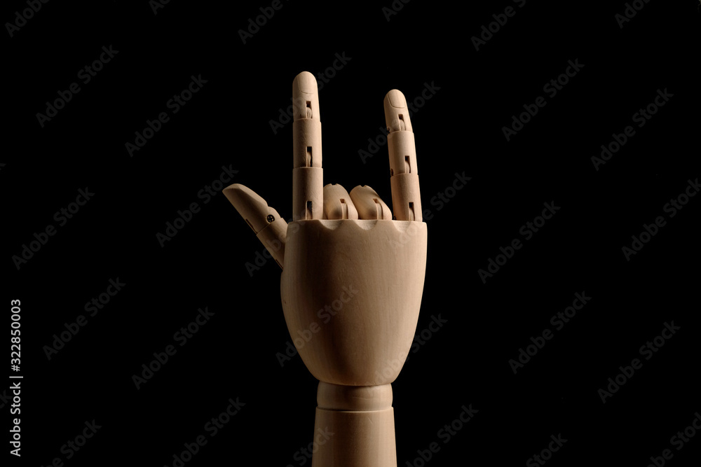 The wooden hand of a mannequin for drawing shows rock n roll sign ...