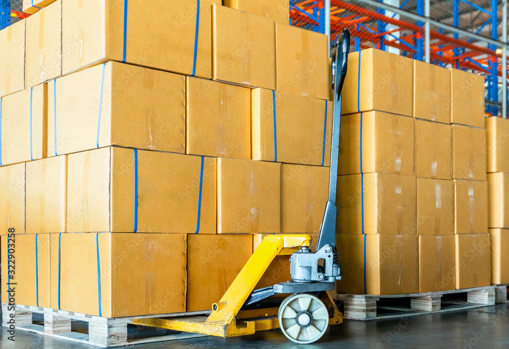 Stack of package boxes on pallets and hand pallet truck in interior ...