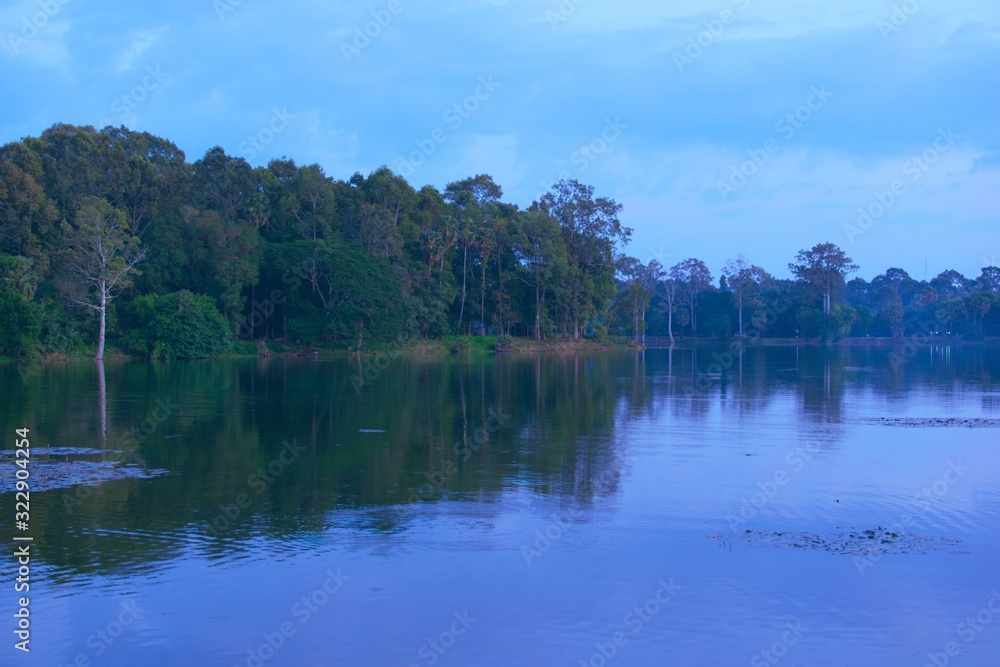 Reflections of the jungle over the broad moat of the ancient city of ...