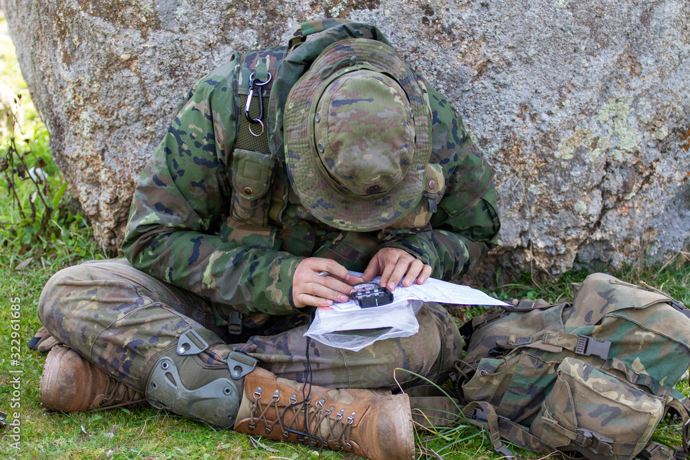 Soldier of the ground army looked at a map with a compass to orient ...