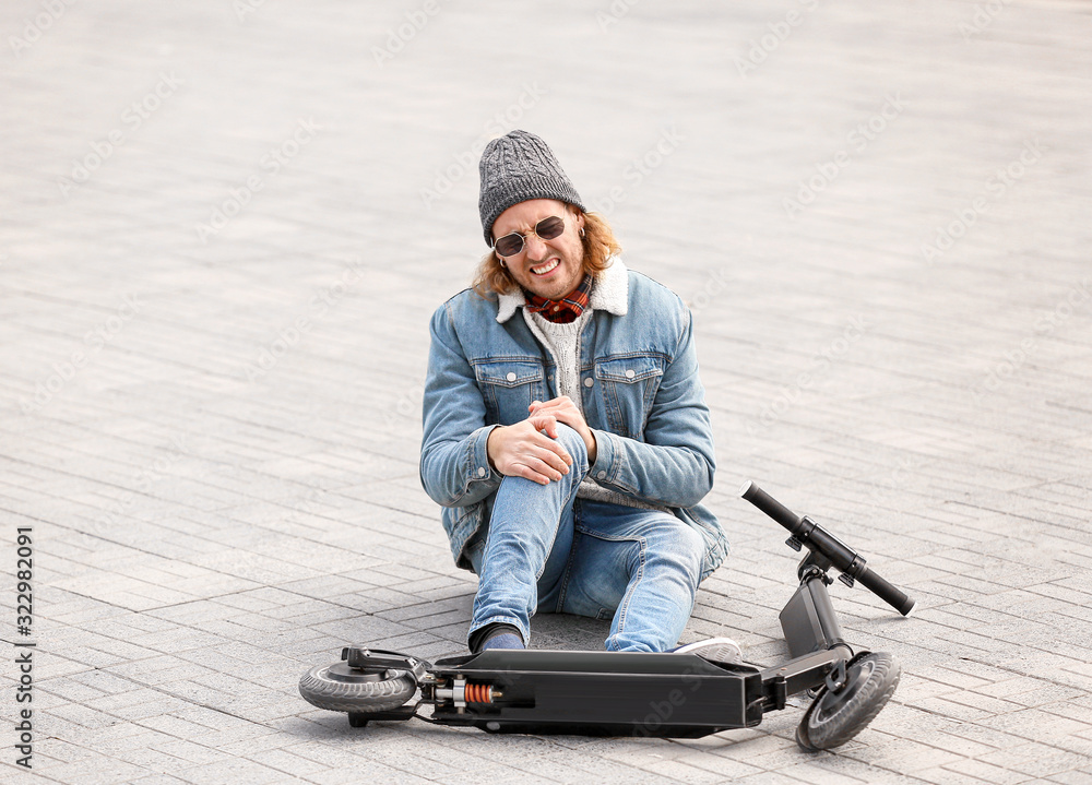 Young man fallen off his kick scooter outdoors Stock Photo | Adobe Stock