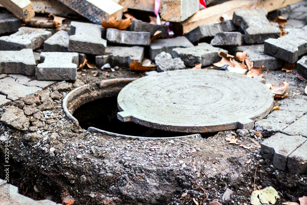 Open sewer manhole and tiles for pavement. Road working. Stock Photo ...