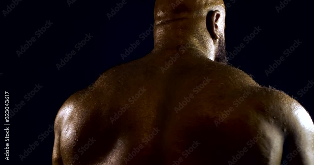 close-up of a male body with bronze skin on a black background. the ...