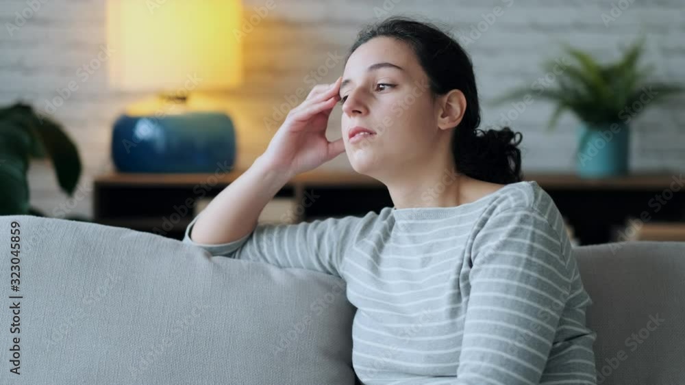 Video of worried young woman thinking while sitting on sofa in the ...