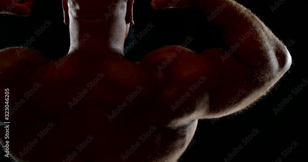 close-up of a man's back and shoulders with bronze skin on a black ...