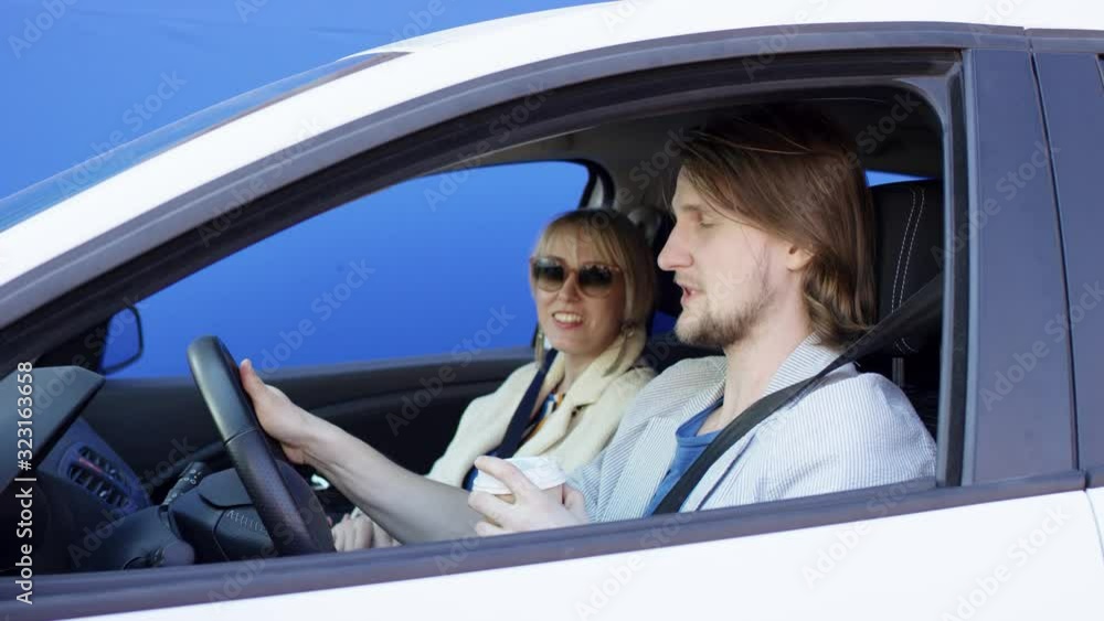 Driving a car man is drinking coffee in paper glass and chatting with ...