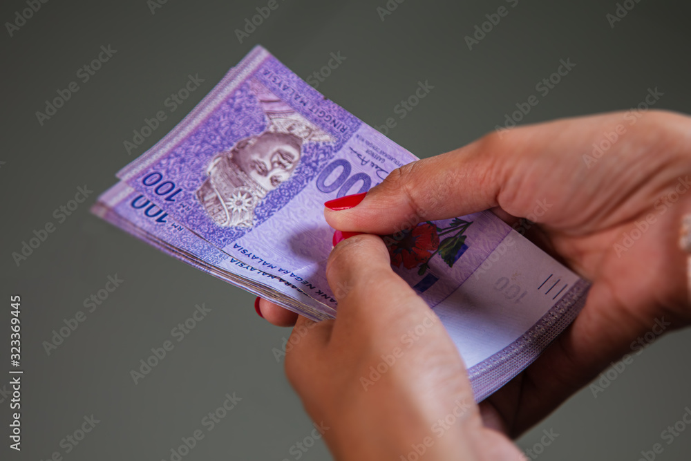 Female Hands with red nails counting 100 Ringgit banknotes. Ringgit the ...
