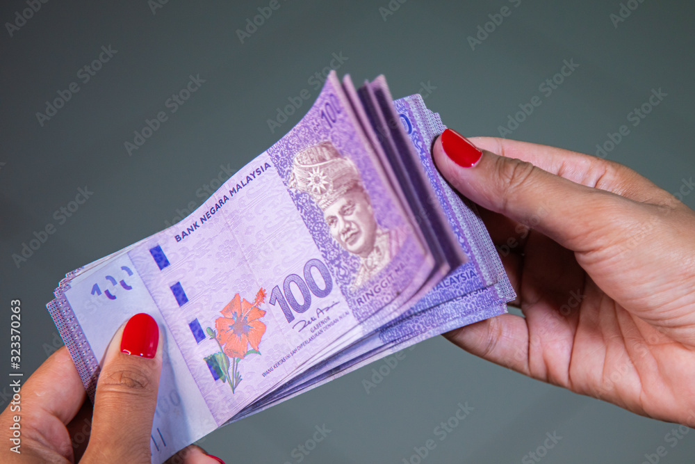 Female Hands with red nails counting 100 Ringgit banknotes. Ringgit the ...
