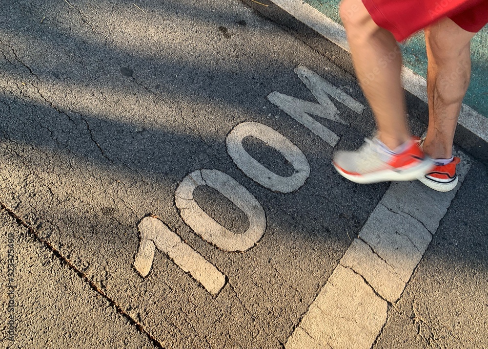 feet of man runner jogging on street with 100 meter sign Stock Photo ...