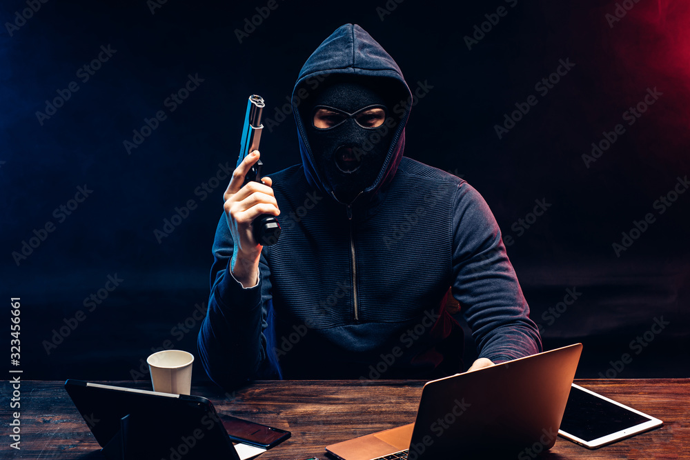 dangerous anonymous hacker man in scary mask sit at table with laptop ...