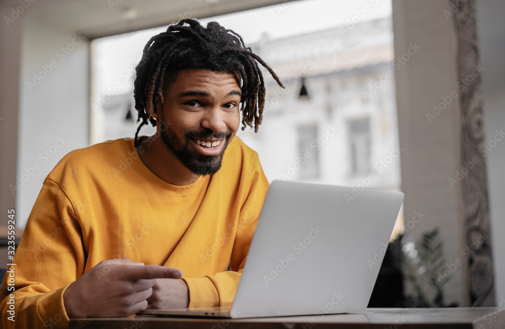 Happy African American man with stylish dreadlocks pointing finger on ...