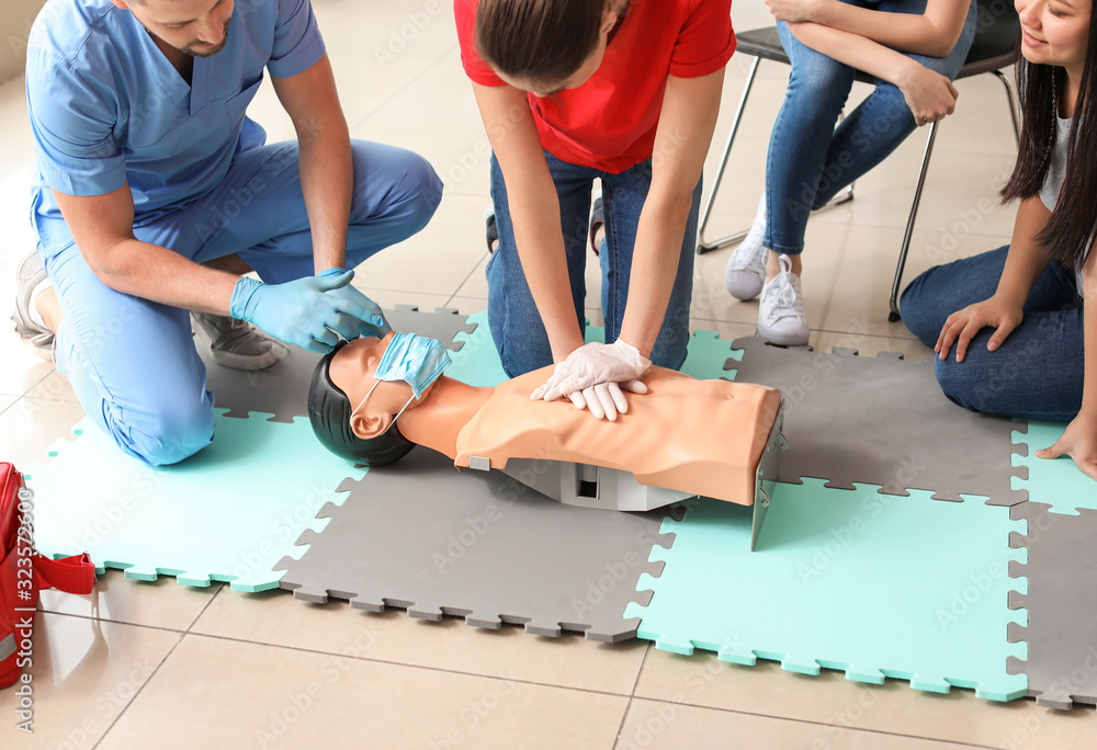 Instructors demonstrating CPR on mannequin at first aid training course ...