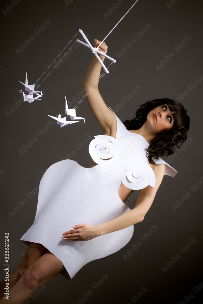 Portrait of a cute young sad girl in origami dress with moving arms ...