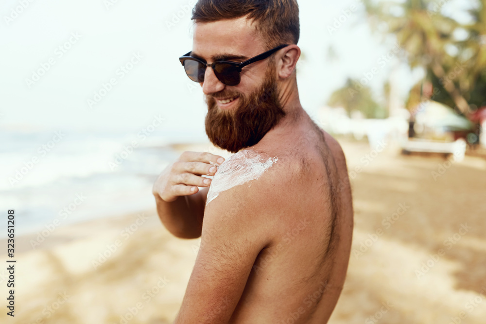 Handsome Man with beard, In Sunglasses Sunbathing With Sunscreen Lotion ...