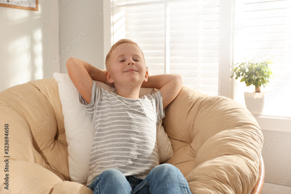 Cute little boy relaxing in papasan chair at home Stock Photo | Adobe Stock
