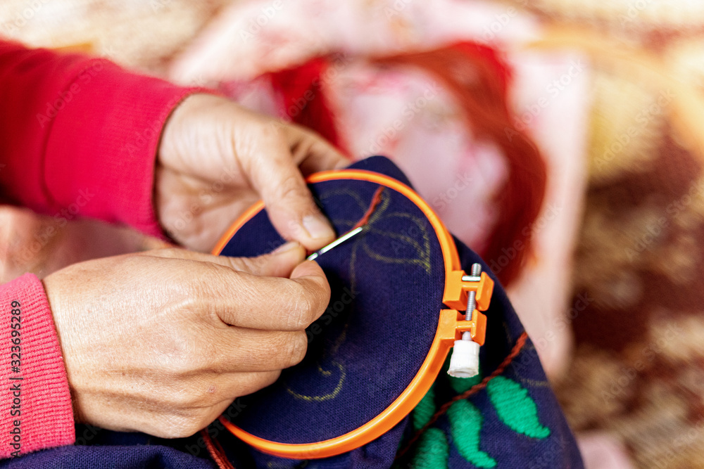 Asian woman's hand is embroidered with tribal native fabric. Sewing ...