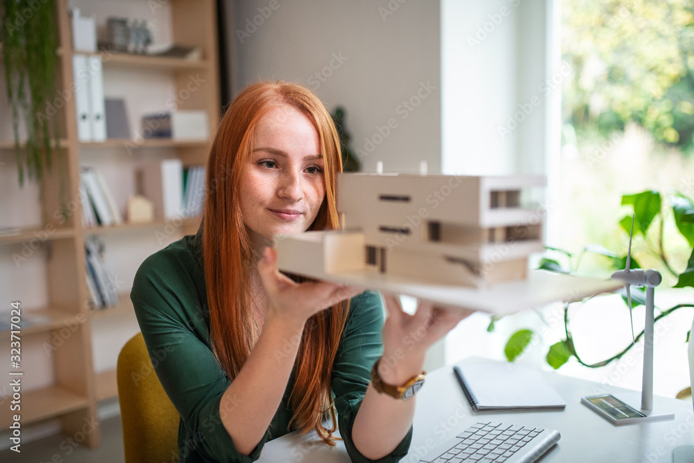 Architect with model of a house sitting at the desk indoors in office ...