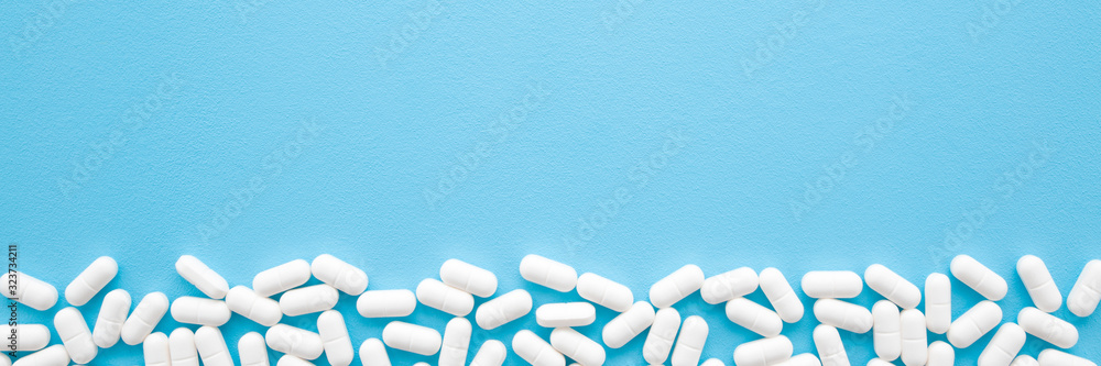 White pills on light pastel blue table. Drugs banner. Medical, pharmacy ...