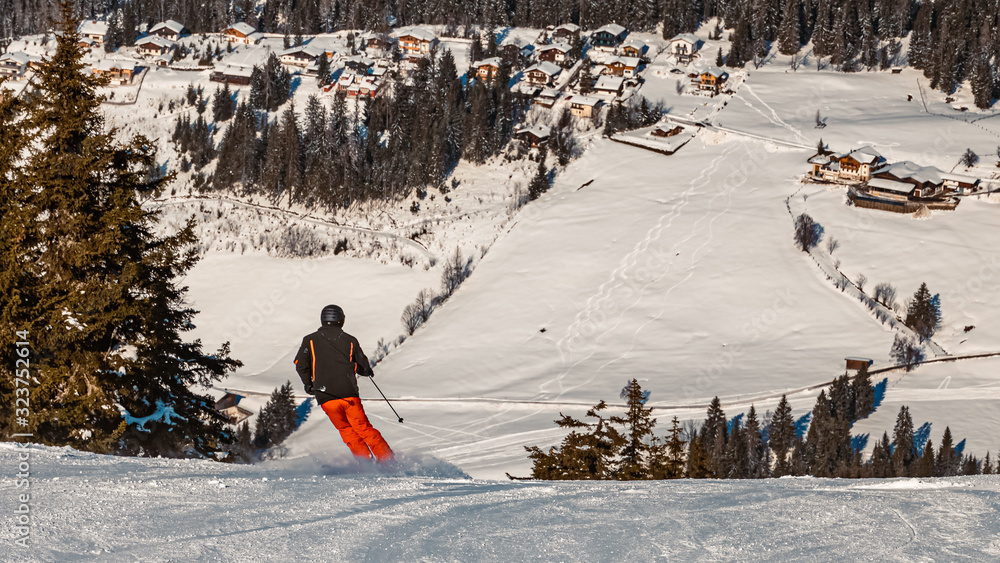 Ski driver making a sharp turn on a terrain edge with flying snow and ...
