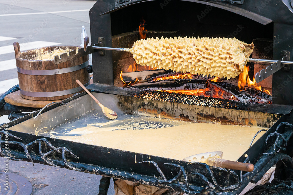 on the street at the wood stove are preparing Lithuanian tree cake ...