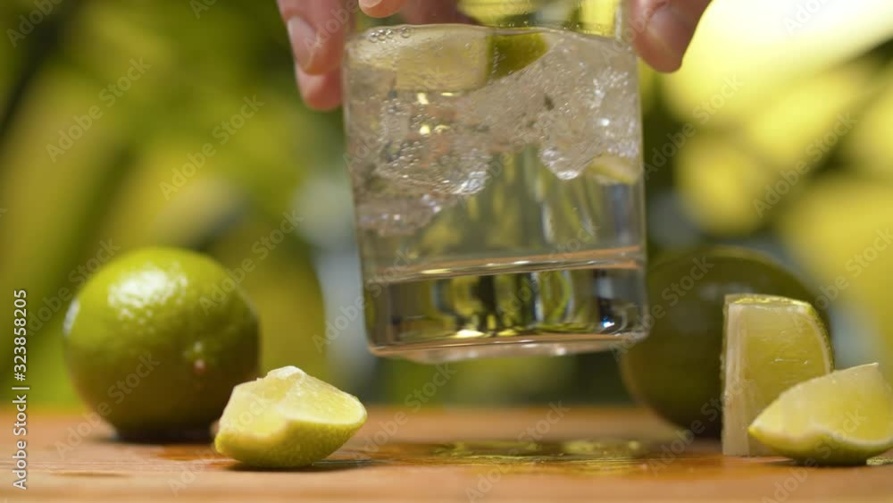 Close up hand shaking a glass of soda water. Tonic fizzy water with ice ...