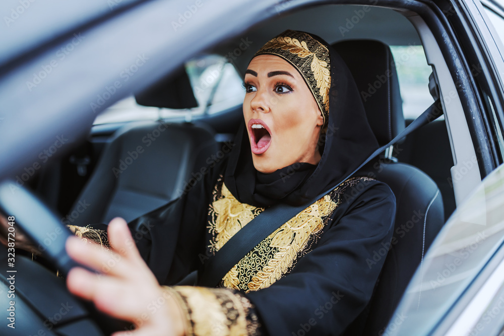 Shocked beautiful muslim woman in traditional wear sitting in her car ...