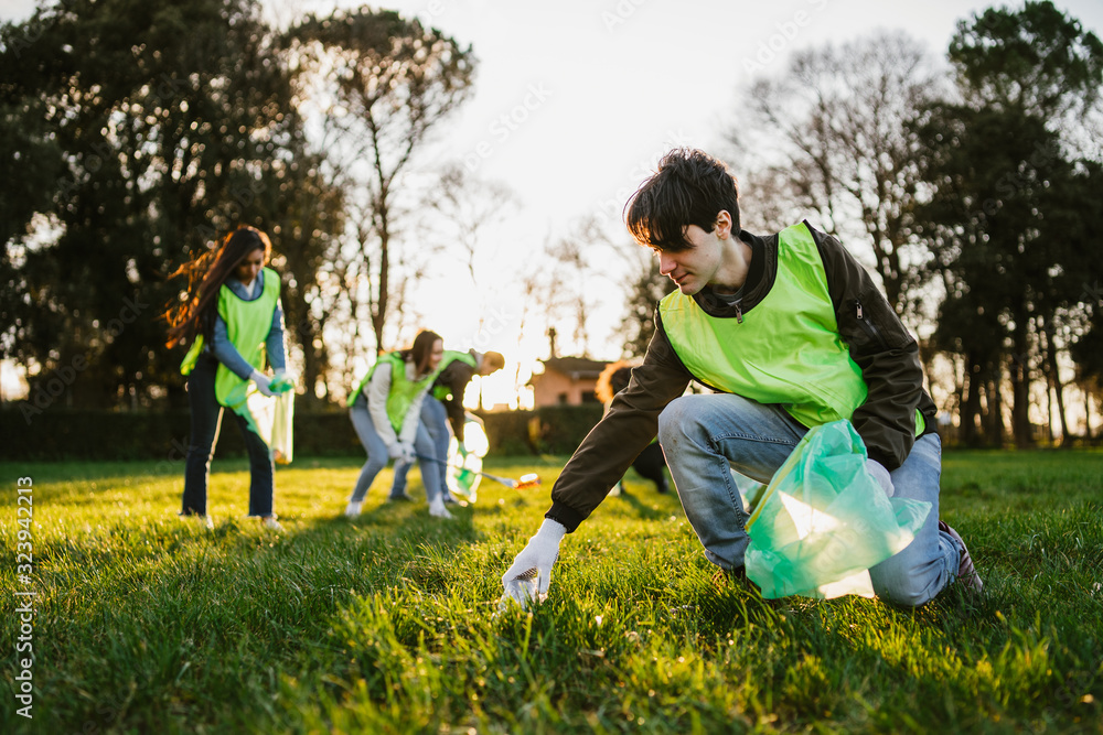 Group of friends during a volunteer garbage collection event in a park ...