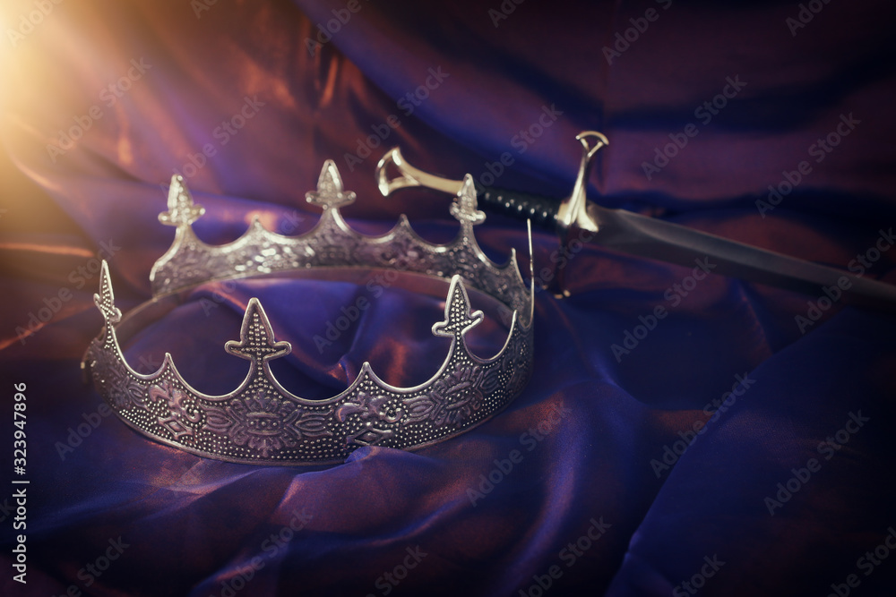 low key image of beautiful queen/king crown and sword over dark royal ...