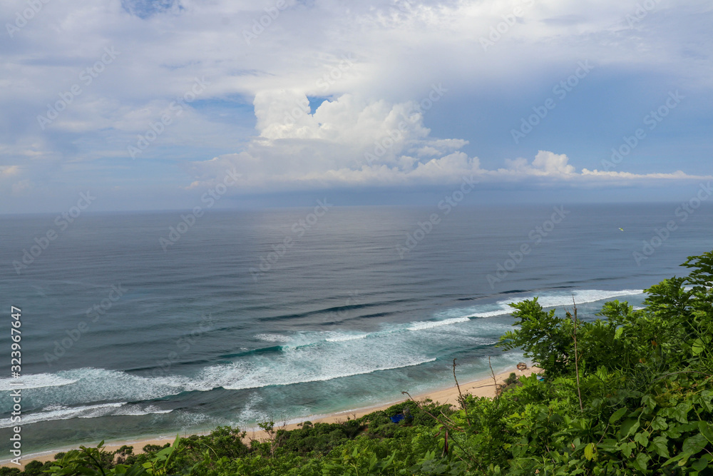A high cliff off the coast of the Indian Ocean on Bali Island overgrown ...