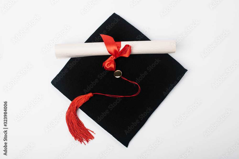 Top view of black graduation cap with red tassel and diploma on white ...
