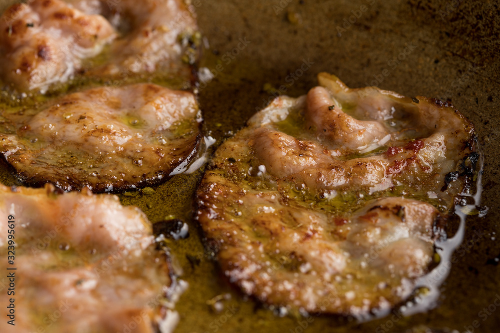 Roasted ham with fat bubbles in the pan, close-up, visible texture of ...