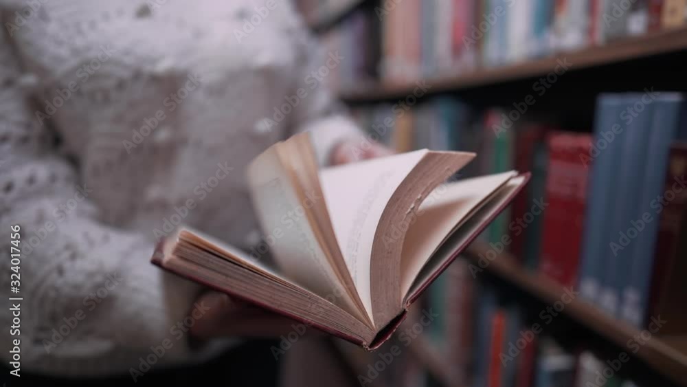 Unrecognizable woman beautifully turns over the pages of old paper book ...