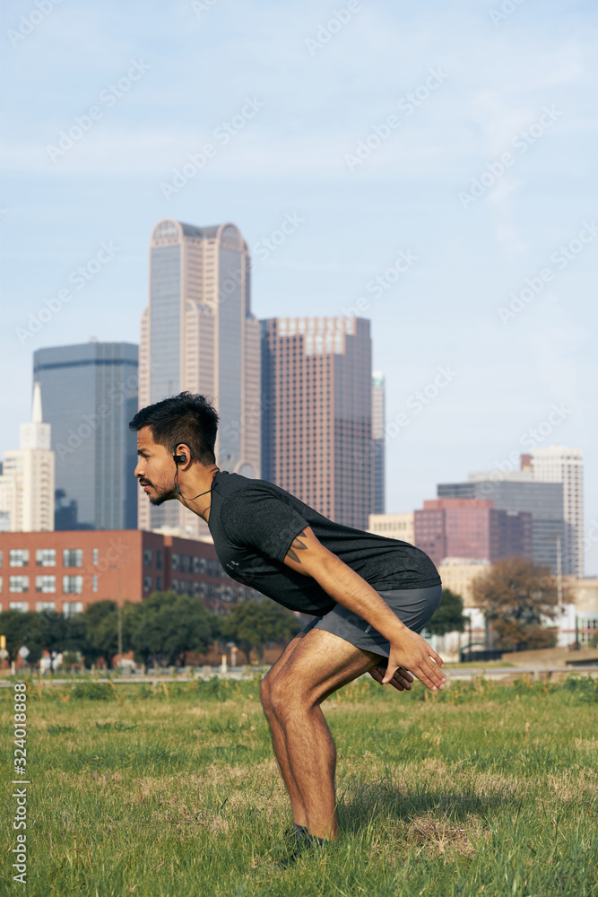 Side view of Hispanic male athlete in active wear jumping with ...
