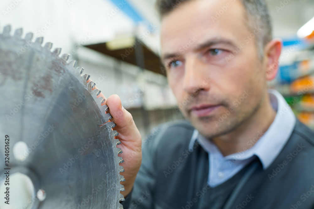 worker inspecting the blade of the circular saw Stock Photo | Adobe Stock